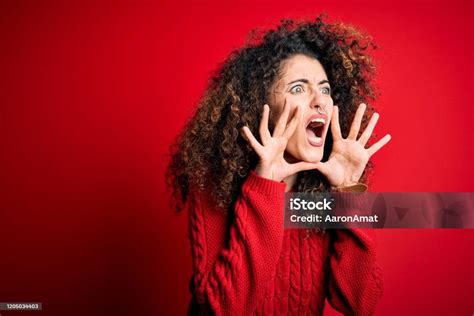 곱슬 머리와 피어싱 캐주얼 빨간 스웨터를 입고 젊은 아름다운 여자는 입 위에 손으로 큰 소리로 외치는 겨울에 대한 스톡 사진 및