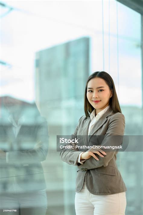 우아한 양복을 입은 자신감 있는 아시아 사업가의 초상화가 현대 사무실의 창문 근처에 팔짱을 끼고 서 있습니다 25 29세에 대한 스톡 사진 및 기타 이미지 Istock