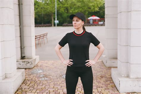 영 운동 아름 다운 여 자가 검은 유니폼과 모자 스포츠 연습을 하 고 도시 공원 야외에 서 실행 하기 전에 워밍업에 집중 휘트니스 건강 한 라이프 스타일 개념입니다 가냘픈에