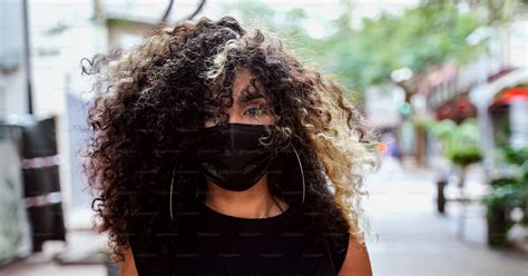 아프리카 여자는 질병 코로나바이러스에 대한 수술용 마스크를 쓰고 도시 거리를 걷고 있다 팬데믹 기간 동안 사회적 거리두기를 존중하는 안면 마스크를 쓴 소녀 사진