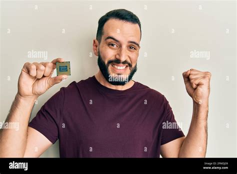 Young Man With Beard Holding Cpu Computer Processor Screaming Proud Celebrating Victory And