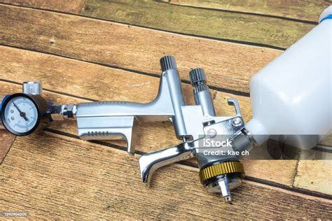 나무 바닥에 페인트 스프레이 산업 회화 및 코팅에 사용되는 산업 크기 스프레이 건을 들고 화가의 팔 손의 이미지 배경 클리핑