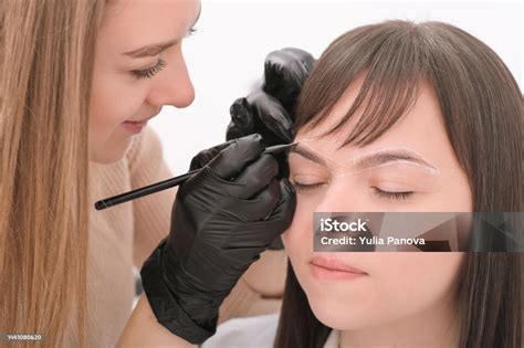 마이크로 블레이딩 또는 헤나 문신 클로즈업 전에 눈썹 표시 및 측정 화이트 브로우 페이스트 스레딩 고객과 함께 전문적인 젊은