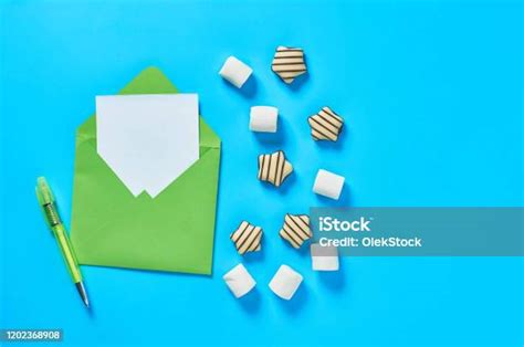 흩어져있는 줄무늬 사탕 펜 근처의 마시멜로 빈 종이 시트가있는 녹색 봉투가 파란색 책상 위에 놓여 있습니다 러브 레터 컨셉 맨 위 보기 갈색에 대한 스톡 사진 및 기타