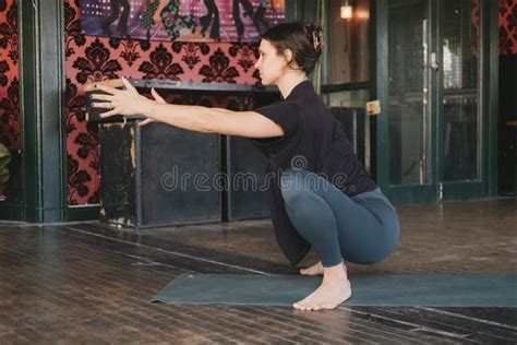 Female Yogi New Teacher In Malasana Squat Or Garland Pose In Her Yoga