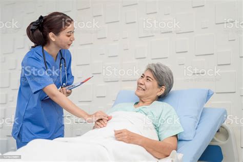 여성 간호사 또는 의사가 환자의 침대에 누워 심장 및 호흡 검사를하는 노인 여성 환자를 돌보고 있습니다 그리고 환자는 미소를 지었다 2명에 대한 스톡 사진 및 기타 이미지