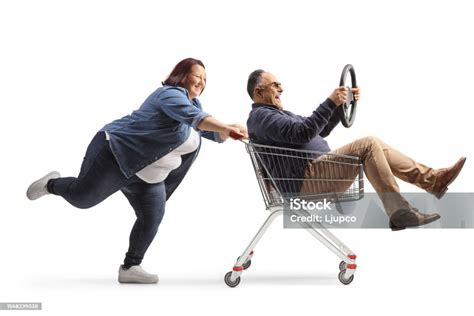 쇼핑 카트 안에 핸들이 달린 성숙한 남자를 밀고 있는 여성의 전체 길이 프로필 샷 25 29세에 대한 스톡 사진 및 기타 이미지