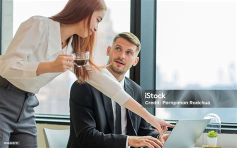 잘 생긴 사업가와 아름다운 여자 또는 비서가 정장을 입고 아침에 사무실에서 함께 일이나 프로젝트에 대해 논의하고 노트북을 사용하고 커피 한 잔을 들고 창가에 앉아 있다 2