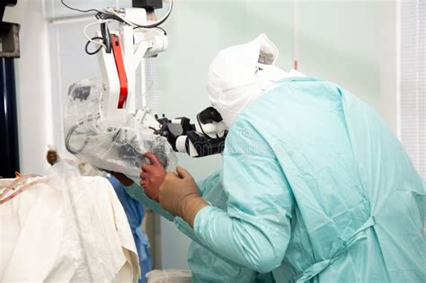 A Neurosurgeon Doctor Looks Into A Microscope During An Operation