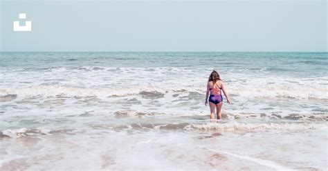 비키니를 입은 여자가 바다로 걸어 들어가고 있다 사진 Unsplash의 무료 바닷가 이미지