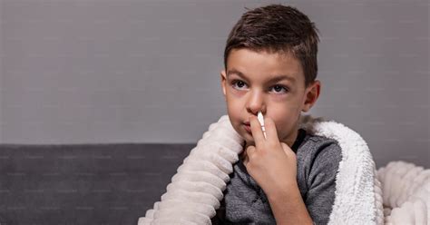 아이는 독감에 걸렸고 비강 스프레이를 사용하여 자신을 돕고 있습니다 비강 스프레이를 사용하는 소년 감기에 도움이되는 비강