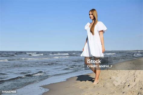 행복한 미소를 짓는 아름다운 여자가 하얀 여름 드레스를 입고 바다 해변을 걷고 있다 18 19세에 대한 스톡 사진 및 기타 이미지 18 19세 건강한 생활방식 걷기