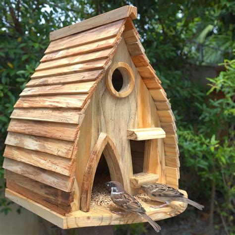 Two Birds Sitting On Top Of A Wooden Bird House That Is Made Out Of Wood