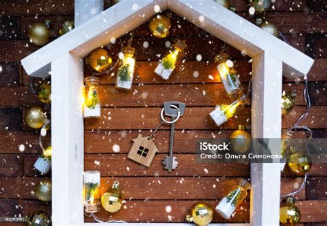 열쇠 고리가 있는 집의 열쇠 크리스마스 장식 레이아웃이 있는 나무 배경의 작은 집 새해 크리스마스를 위한 선물 건물 프로젝트 새 집으로 이사 모기지 임대 및 부동산 구매