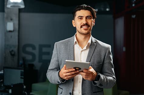 사무실에 서서 디지털 태블릿으로 일하는 젊은 성공한 사업가 25 29세에 대한 스톡 사진 및 기타 이미지 25 29세 Brand Name Smart Phone 경영자