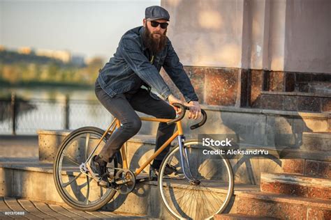 수염 난된 남자와 수정 자전거입니다 선글라스와 모자 일몰에 도시 공원에서 빈티지 자전거를 타고 Gourgeous 큰 수염과 젊은