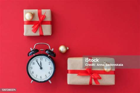 검은 둥근 시계의 평평한 평지와 리본이달린 선물 상자 2개 빨간 배경의 각도처럼 놓인 황금색 작은 공 개념에 대한 스톡 사진 및