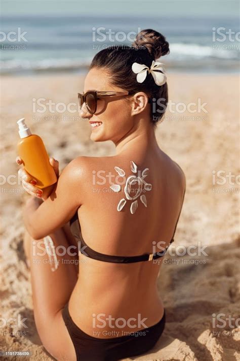 피부 관리 자외선 차단 소녀는 선크림을 바릅니다 심장의 형태로 수영장에서 선탠 로션을 가진 여자 어깨에 그려진 태양이 있는