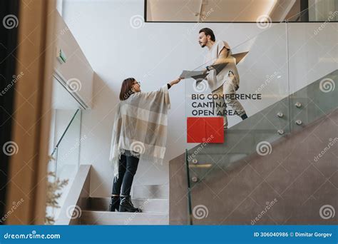 Lovely Woman Meeting Her Male Colleague On The Stairs And Passing Him A