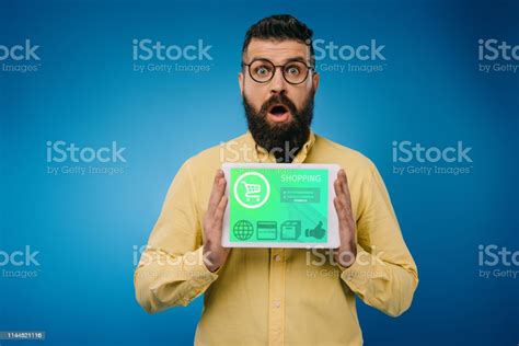 충격 수염 남자는 블루에 고립 된 쇼핑 응용 프로그램과 함께 디지털 태블릿을 제시 놀라움에 대한 스톡 사진 및 기타 이미지 놀라움 디지털 태블릿 사용하기 멀티미디어