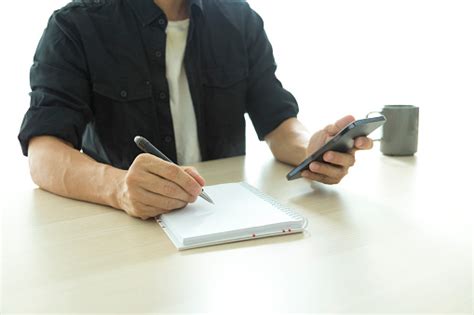 젊은 남자가 카페 레스토랑에서 책상에 커피 컵을 들고 디지털 모바일 스마트 폰을 쓰고 작업합니다 45 49세에 대한 스톡 사진 및 기타 이미지 Istock