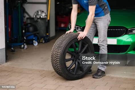 남자 정비공의 중간 선택은 자동차에서 바퀴를 굴립니다 자동차 서비스에서 타이어 교체 자동차 서비스 개념 건물 외관에 대한 스톡 사진 및 기타 이미지 Istock