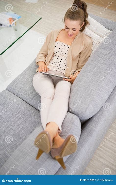 Счастливая женщина кладя на софу и используя ПК таблетки Стоковое Изображение изображение