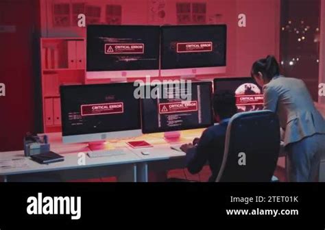 Rear View Of Two Young Diverse Cyber Security Specialists Fixing Critical Error Warning Alarm Rear View Of Two Young Diverse Cyber Security Specialists Fixing Critical Error Warning Alarm