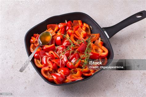 얇게 썬 빨간 피망 양파 신선한 타임 꿀 숟가락을 베이지색 질감의 배경에 얹은 프라이팬 맛있는 고추 타르트 또는 기타 야채