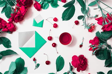 홍차 익은 체리 흰색 바탕에 녹색 잎 장미 누워 있는 작은 봉투 작업 하는 동안 마시는 차 음료를 치유 향기로운 아침입니다 베리 설탕에 절인 과일입니다 평면 위치 최고 볼