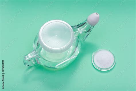 Neti Pot With Soft Comfort Tip And Pile Of Saline Sodium Bicarbonate And Sodium Chloride On
