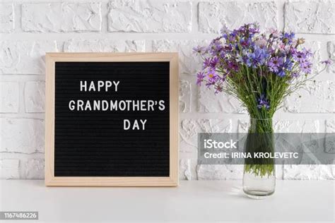 행복 할머니의 날 텍스트 검은 편지 보드에 흰색 벽돌 벽에 대한 테이블에 꽃병에 푸른 꽃다발 파란색 꽃 개념 어머니의 날입니다 인사말 카드 엽서 템플릿 0명에 대한 스톡