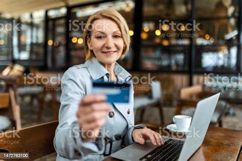 커피숍에서 카메라를 보고 있는 신용 카드로 지불하는 중년 사업가 50 54세에 대한 스톡 사진 및 기타 이미지 50 54세 젊은 여자 2명 Istock