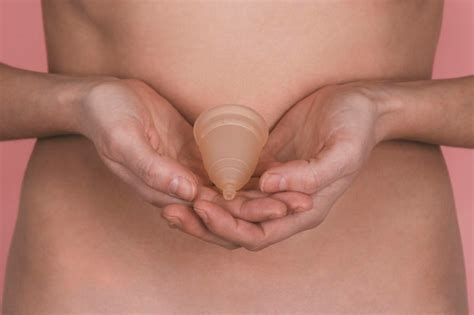 분홍색 배경을 가진 손에 생리컵을 들고 있는 벌거벗은 백인 여성 제로 폐기물 개념입니다 개념 여자입니다 지속 가능성의 개념