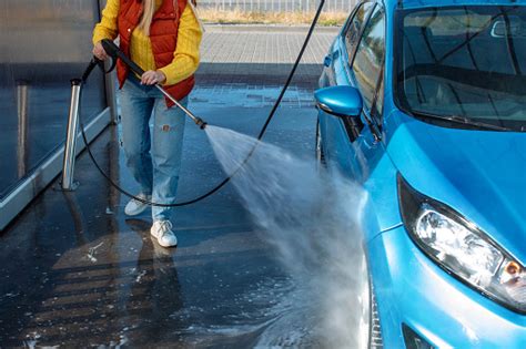 수동 세차 셀프 서비스 스테이션에서 자동차를 씻고 거품 압력으로 청소하는 젊은 미소 행복하고 매력적인 여성 초상화 운송 자동차