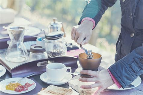 아시아 여성은 자연 녹색 배경 이차가운 느낌과 자연에서 휴식을 취하면서 테이블에 커피 콩을 분쇄하기위한 수동 분쇄기 커피에 손을 구이에 대한 스톡 사진 및 기타 이미지