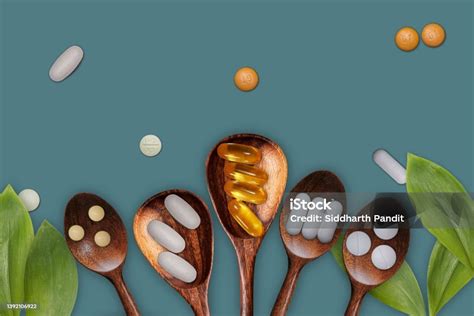 녹색 잎이있는 평범한 파란색 배경에 나무 숟가락에 다양한 비타민 알약 건강관리와 의술에 대한 스톡 사진 및 기타 이미지 건강관리와 의술 건강한 생활방식 아픔 Istock