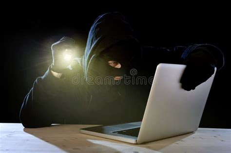 hacker man in black hood and mask with computer laptop hacking system