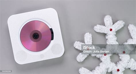 회색 배경에 흰색 눈송이와 함께 크리스마스 음악을 재생하는 분홍색 Cd 디스크가 있는 세련된 흰색 휴대용 컴팩트 Cd 플레이어 레트로 빈티지 트렌드 디스크 플레이어 평면도