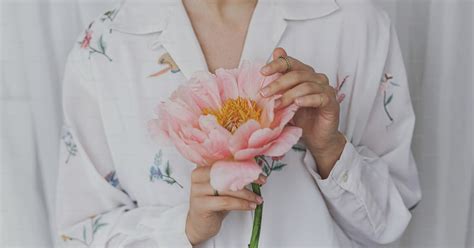 손에 분홍색 모란을 가진 관능적 인 아름 다운 여자입니다 보헤미안 꽃 셔츠를 입은 젊은 세련된 여성이 큰 모란 꽃을 부드럽게 들고 있다 부드러운 부드러운 이미지 봄의