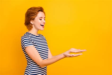 닫 다 사이드 프로필 사진 아름 다운 그녀의 레이디 손 팔 손바닥 빈 공간 새로운 제품 흥분 착용 캐주얼 스트라이프 화이트 티셔츠 의상 옷 고립 된 노란색 밝은 배경 받기에