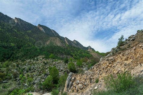 Jagged Rocky Ridge Covered With Sparse Forest Against A Blue Sky