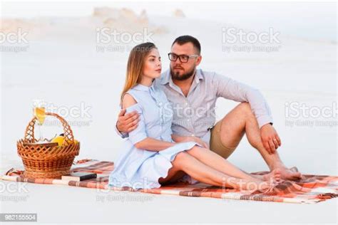 모래 해변 담요 해변에서 피크닉을 즐기는 행복 한 커플에 앉아 행복 한 부부와 여름 휴가에 좋은 시간을가지고 멋진 매력적인 커플은 화이트에 함께 앉아 과일에 대한 스톡 사진