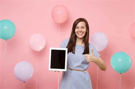 블루 드레스를 입고 화려한 공기 풍선 파스텔 핑크 배경에 엄지 표시 빈 빈 화면으로 태블릿 Pc 컴퓨터를 들고 웃는 젊은 여자의 초상화 생일 휴가 파티 개념 14에 대한