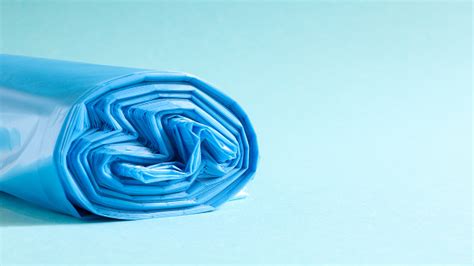 파란색 배경에 파란색 플라스틱 쓰레기 봉투 한 롤 쓰레기에 수납할 수 있도록 설계되어 집에서 사용되며 다양한 쓰레기 통에 보관되는 가방 복사 공간 0명에 대한 스톡 사진 및