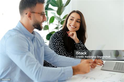 현대식 사무실 책상에서 업무에 대해 토론하고 초점과 관심사를 가지고 재무 차트와 문서를 검토하고 새로운 아이디어와 전략을 개발하고 미소를 짓는 의욕적인 전문직 남녀 20