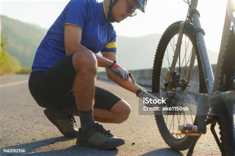 공기 펌프를 사용하여 자전거 바퀴에 공기를 펌핑하는 아시아 자전거 타는 남자 아침에 호수 주변에서 자전거를 타기 전에 준비