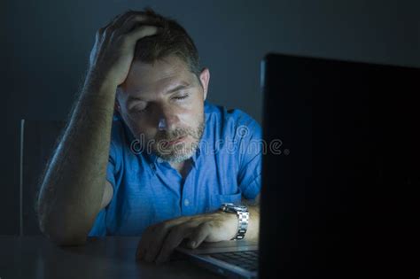 Young Attractive And Tired Unshaven Man Working Late Night On Laptop Computer In The Dark