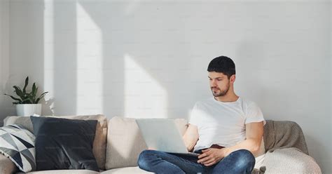 흰 셔츠와 청바지를 입은 남자가 실내에서 노트북을 들고 침대에 앉아 있다 사진 Unsplash의 남자 청바지 이미지