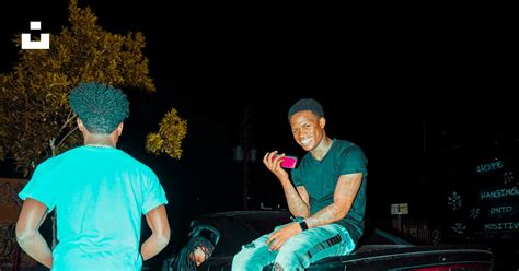 파란색 티셔츠와 파란색 데님 청바지를 입은 남자가 밤 시간에 검은 차 옆에 서 있다 사진 Unsplash의 무료 윈우드 아트 디스트릭트 이미지